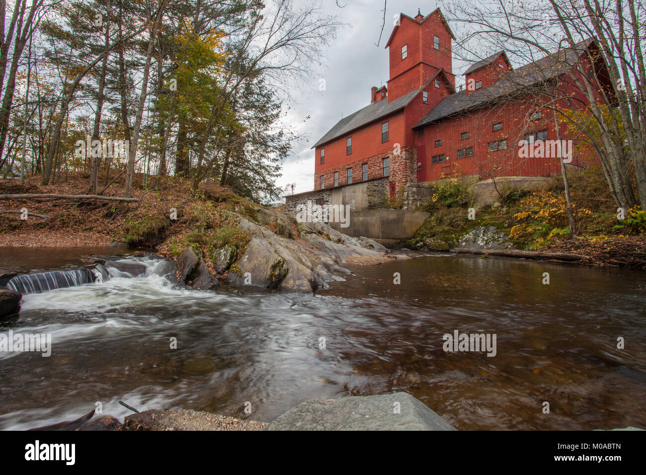 Old red mill building next to a river Stock Photo - Alamy