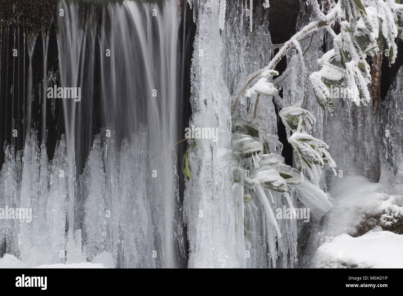 Cold winter day. Waterfall with blurred water flow, rocks in a creek or ...
