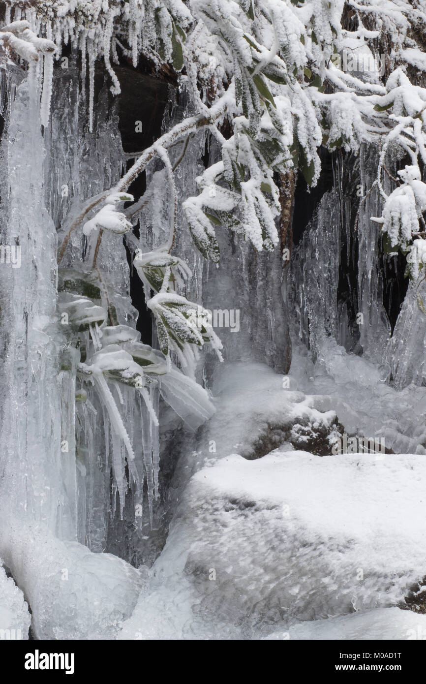 Cold winter day. Waterfall with blurred water flow, rocks in a creek or ...