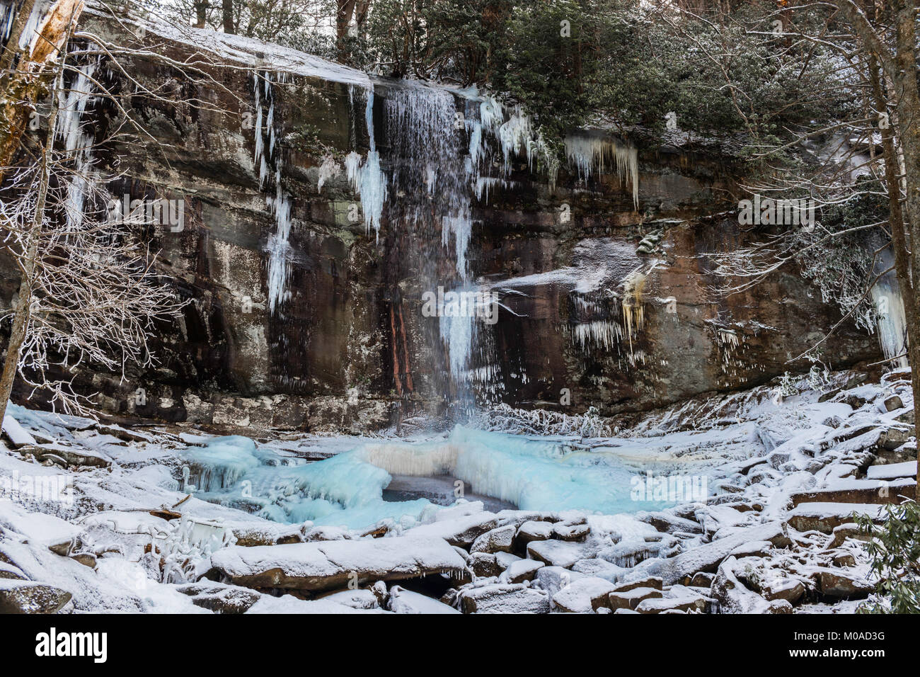 Cold winter day. Waterfall with blurred water flow, rocks in a creek or ...