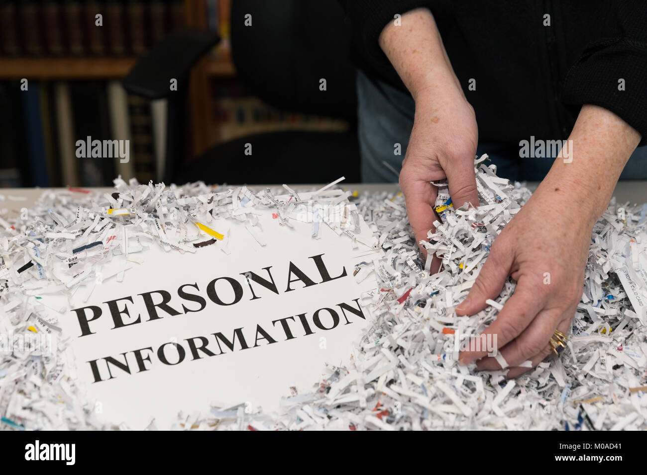 A woman's hands are shown shredding paper with the words PERSONAL ...