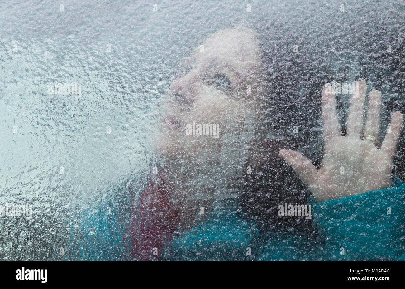 Attractive woman looking through a window covered in thick ice, with ...