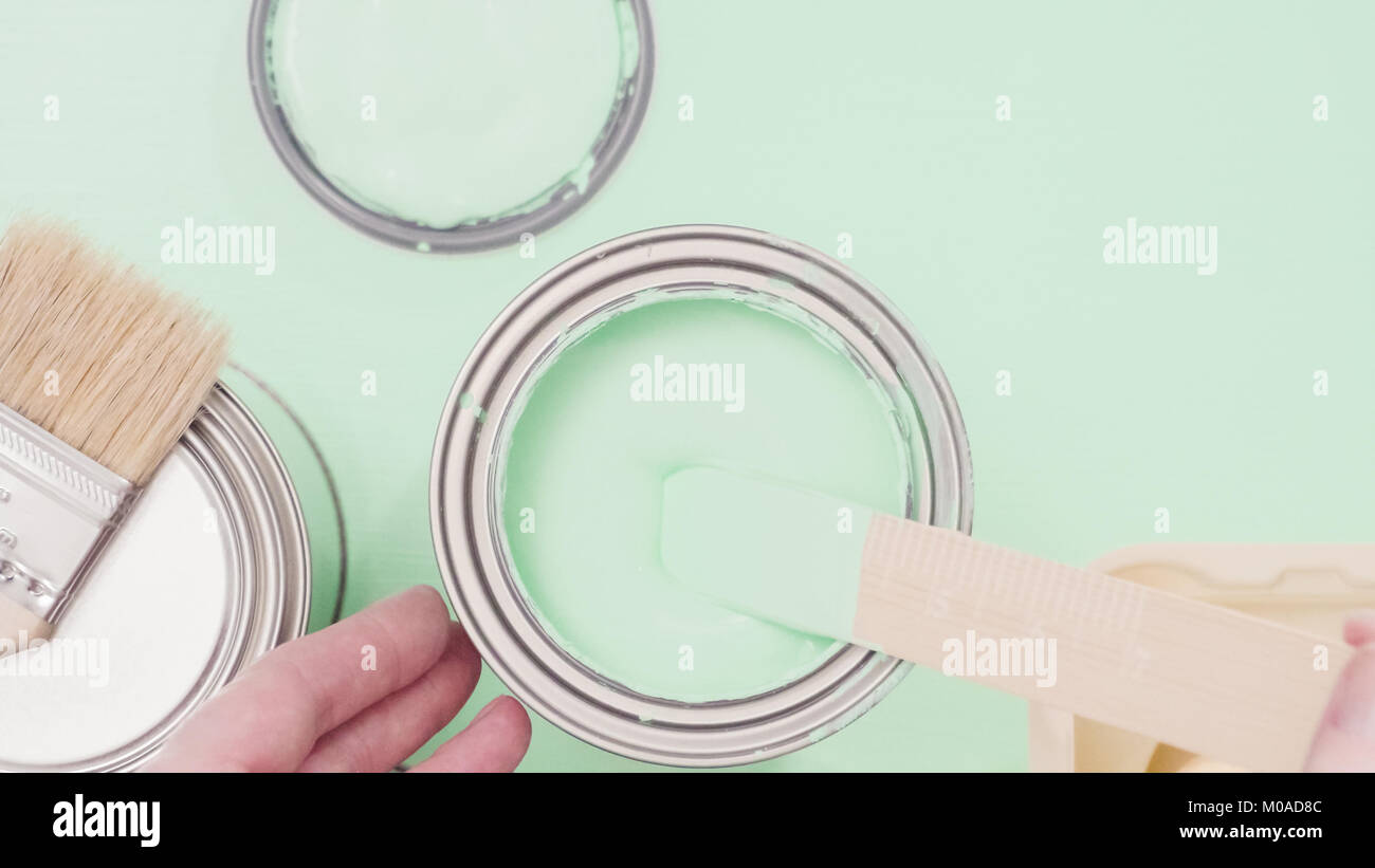 Mixing paint in metal paint can with wooden stick Stock Photo - Alamy