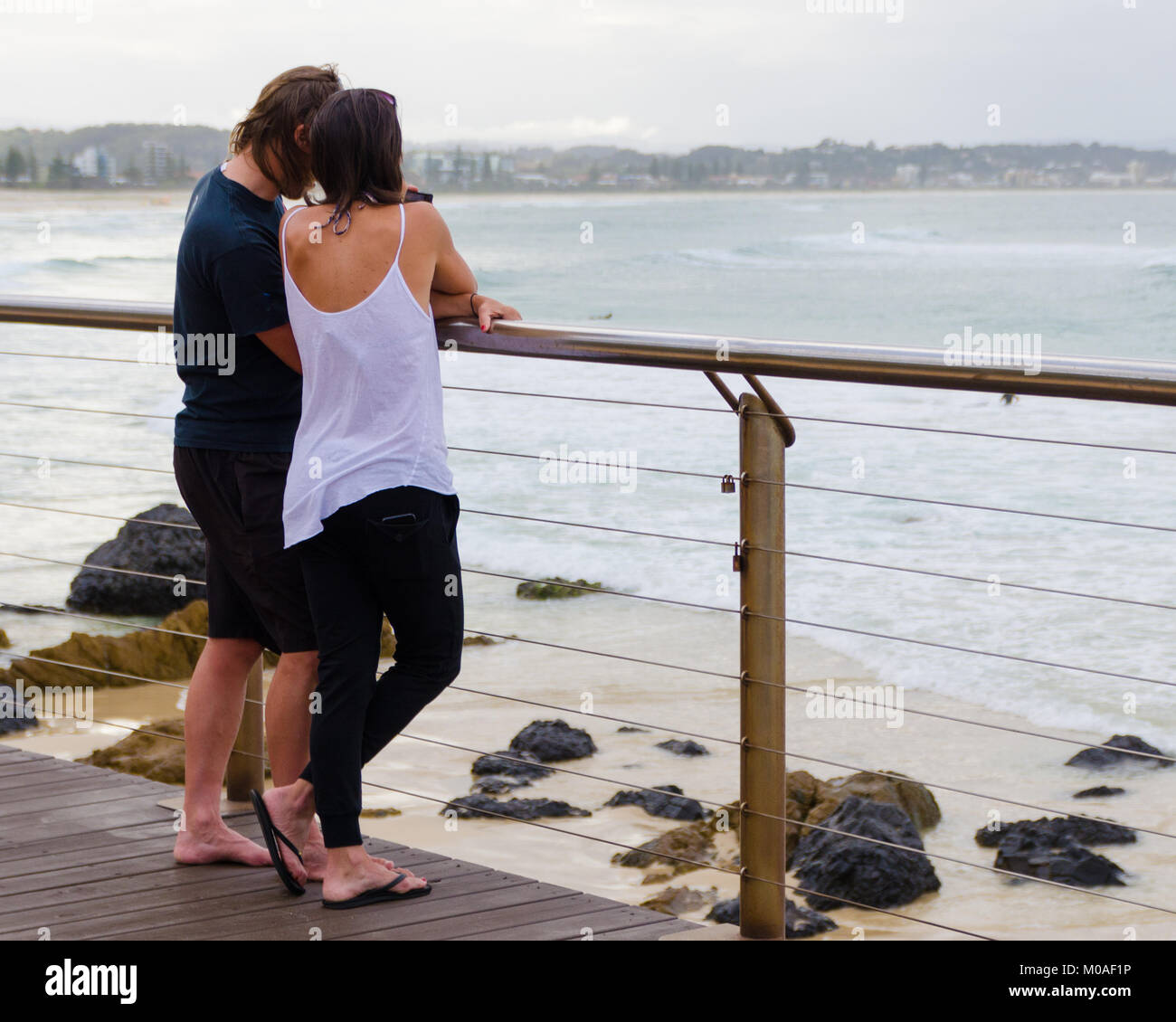 Couple enjoy quiet moment together by the beach. Tourist lean of ...
