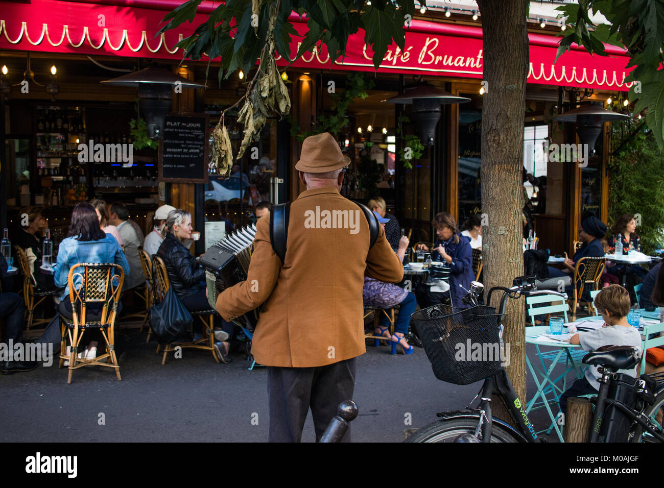 A street artist plays an accordion in front of a café in Paris. October ...