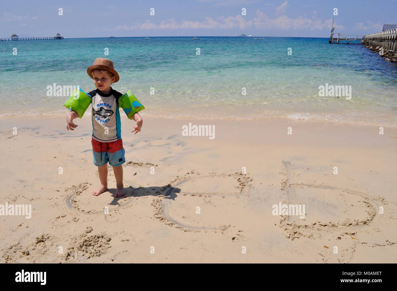 Small boy with armbands and name Seb written in sand on the beach at ...