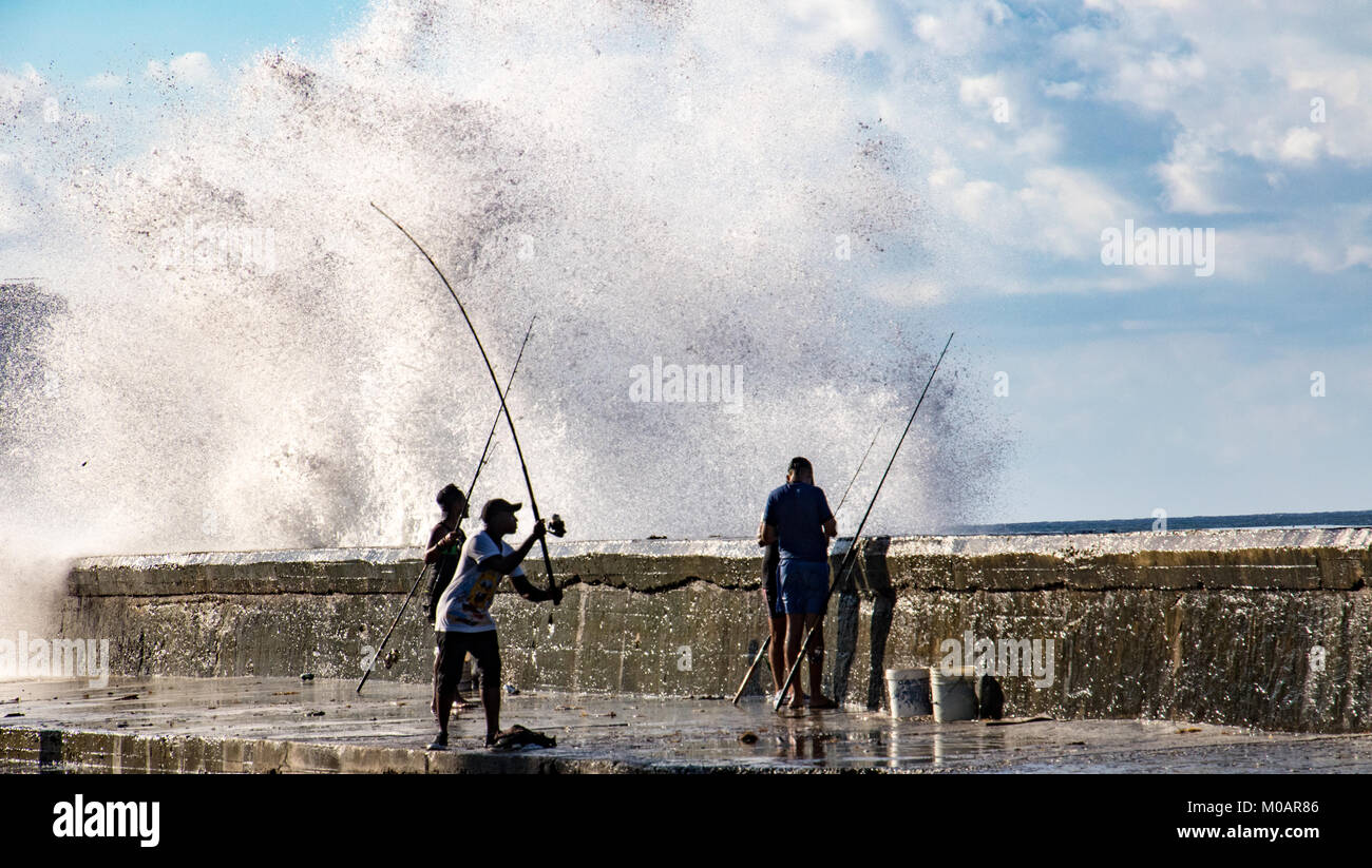 Havana, Cuba, Nov 20, 2017 - Waves crash over the Malecon wall as men ...