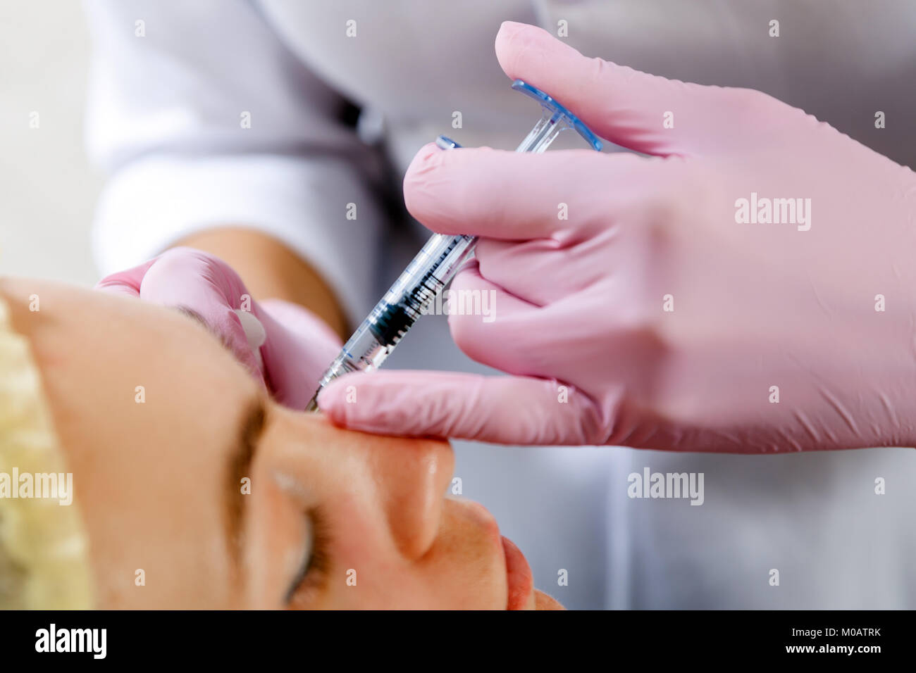 Close-up of a beautician injects Botox injection into the cheekbones of ...