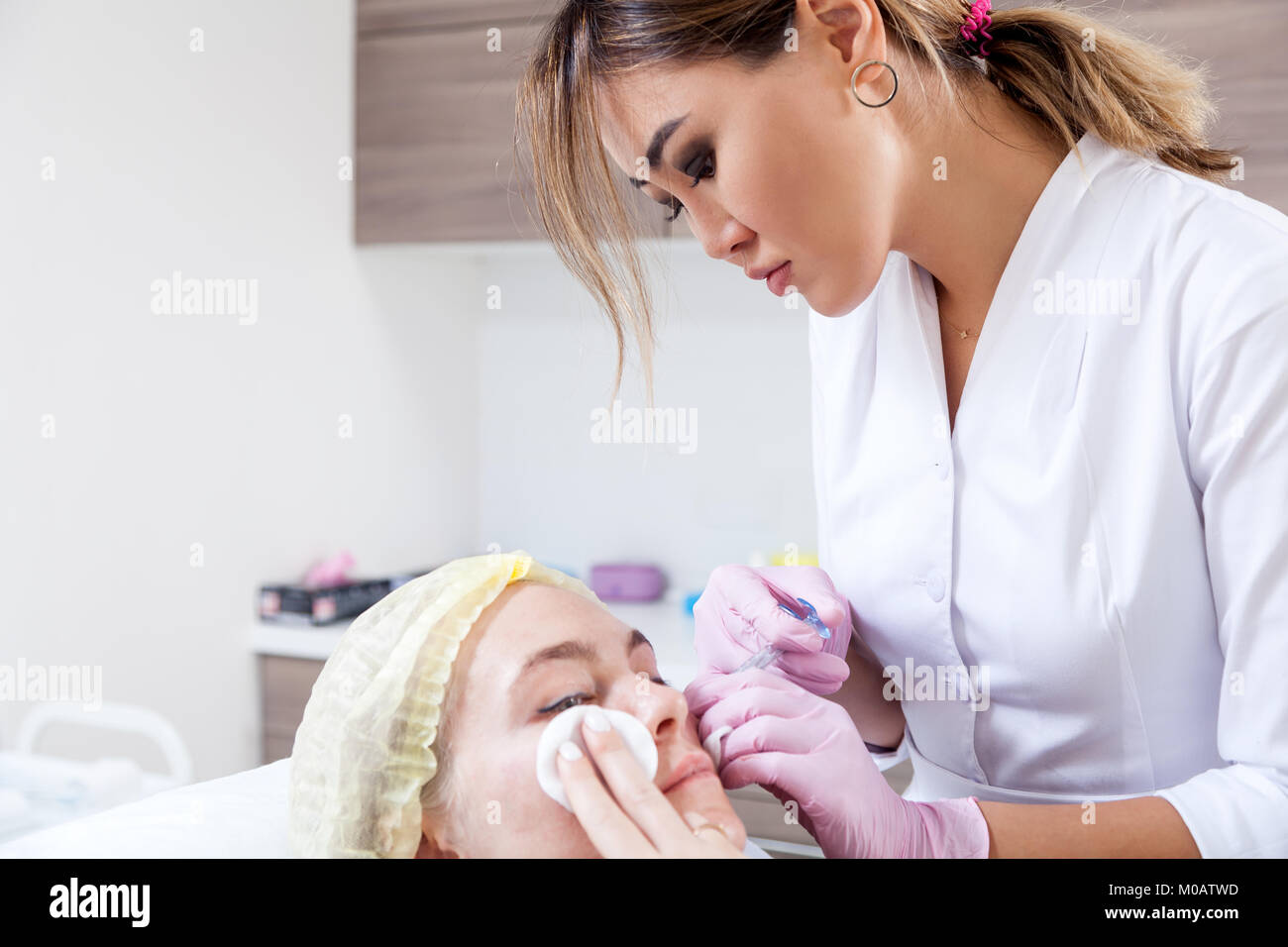 Close-up Young woman doctor cosmetician in white lab coat and sterile ...
