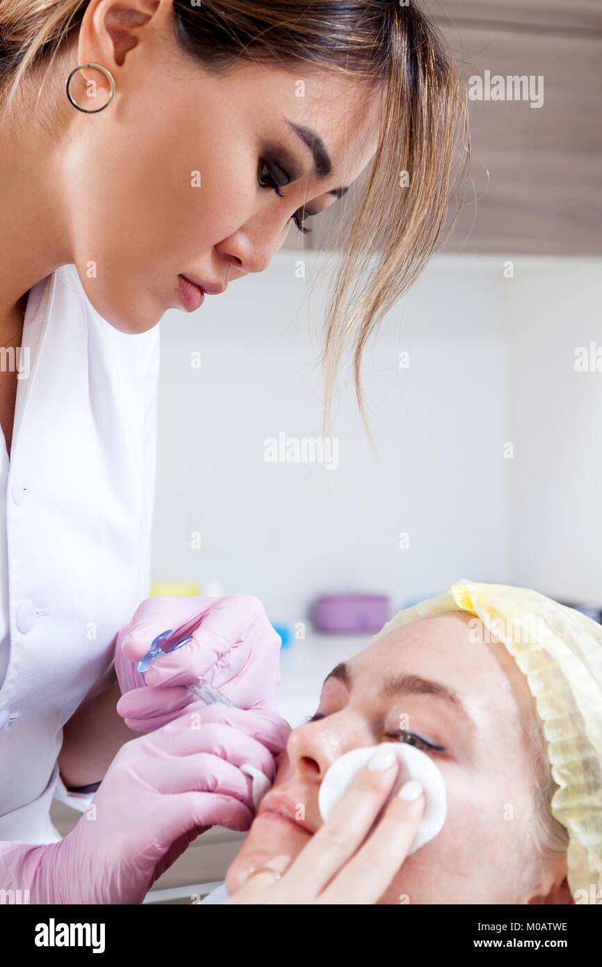 Close-up Young woman doctor cosmetician in white lab coat and sterile ...