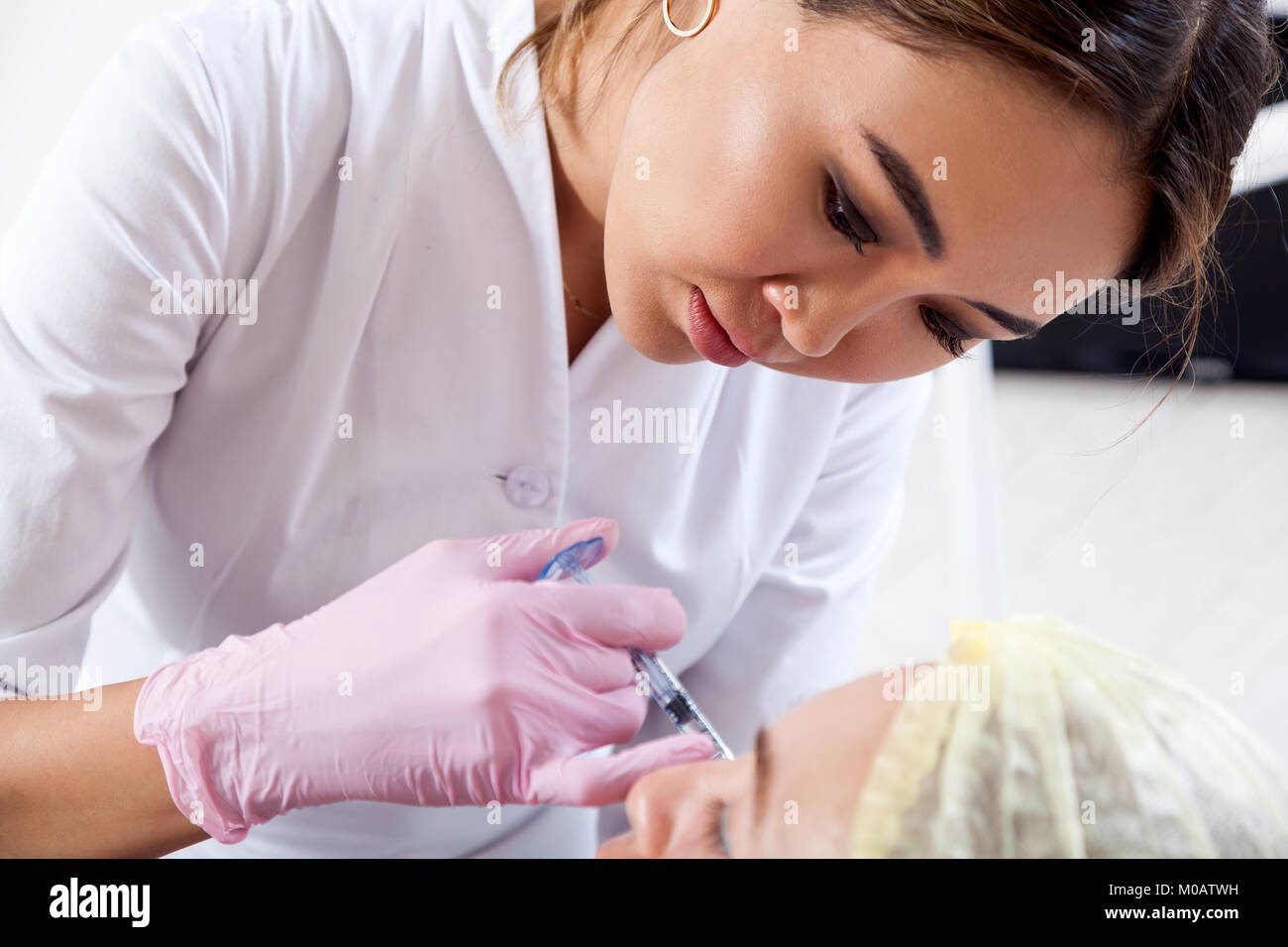 Close-up Young woman doctor cosmetician in white lab coat and sterile ...