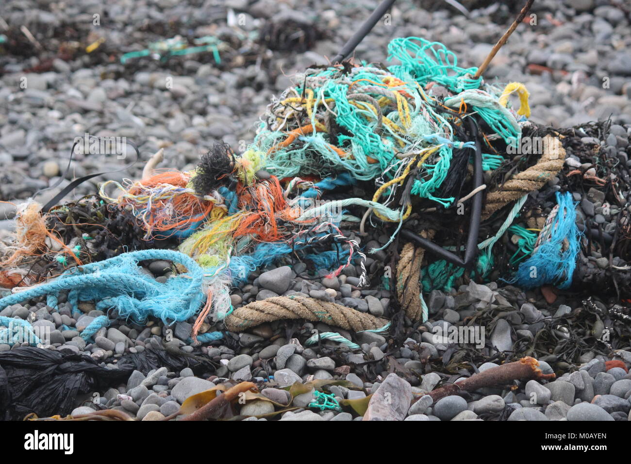 Tangle of fishing nets, ropes and plastic waste on stony beach in Port ...