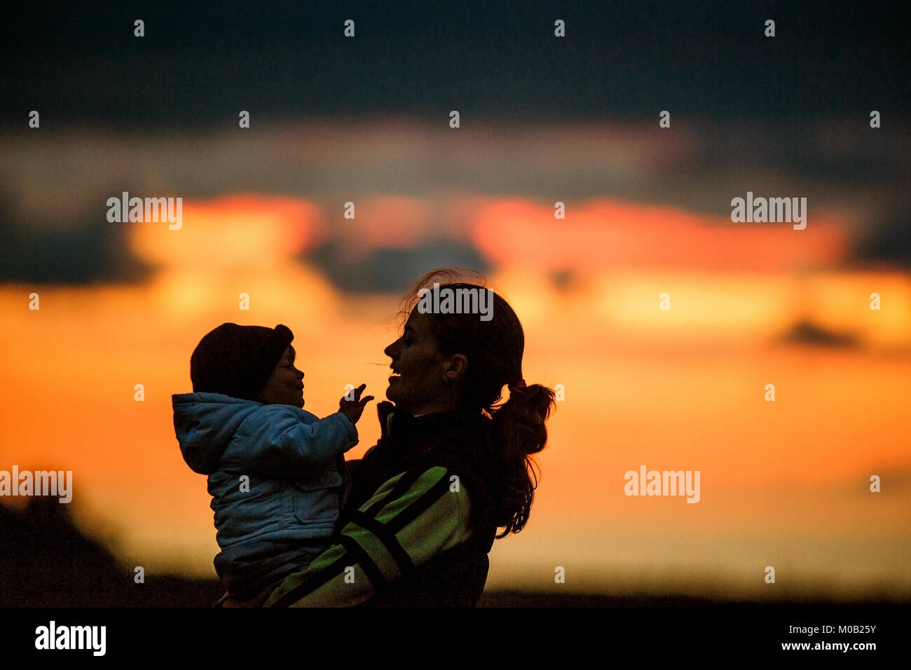 Portrait of happy mother with baby on sunset background, Summer sunset ...