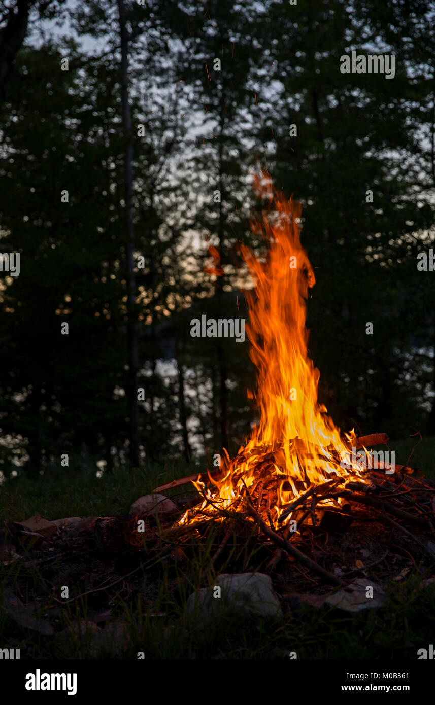 Campfire by the lake early in the evening Stock Photo - Alamy