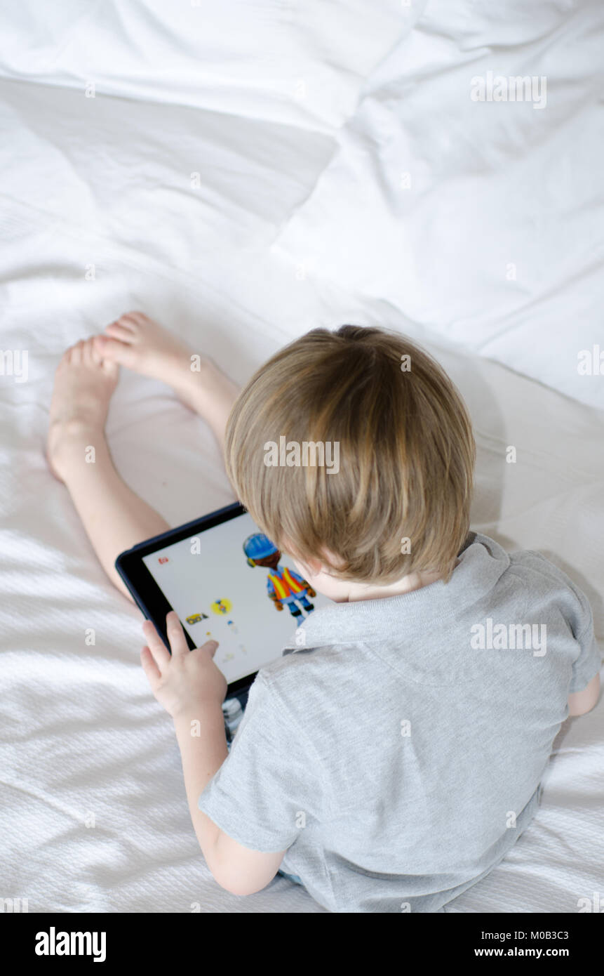 Little boy sitting on the bed and playing on an iPad Stock Photo - Alamy