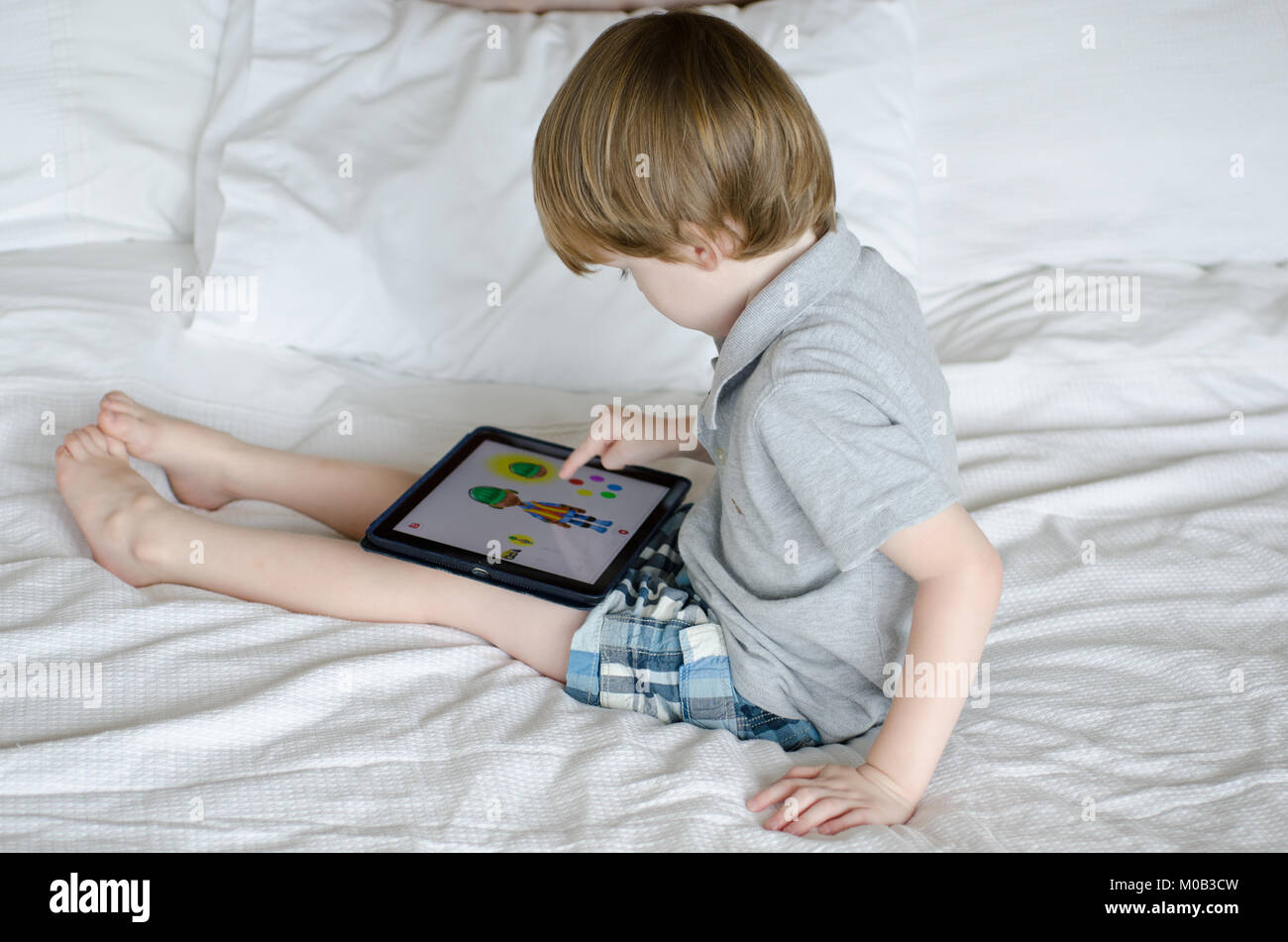 Little boy sitting on the bed and playing on an iPad Stock Photo - Alamy