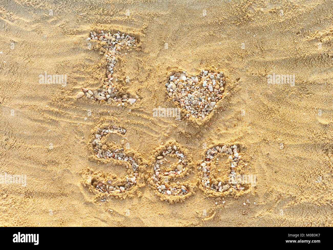 I love sea. Letters and heart made from small stones and seashells on ...