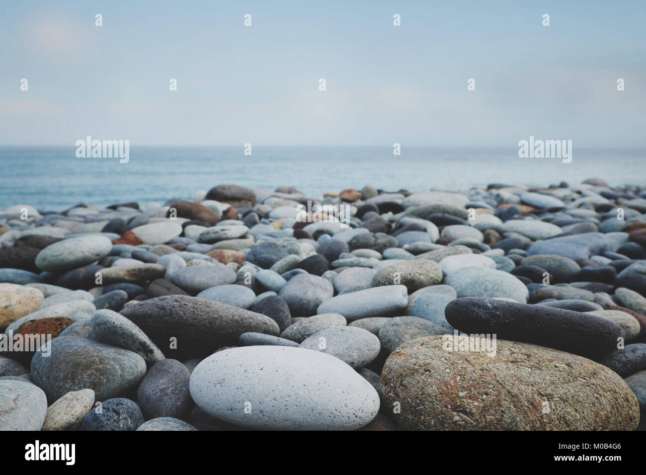 pebble stone beach ocean background blue sky Stock Photo - Alamy