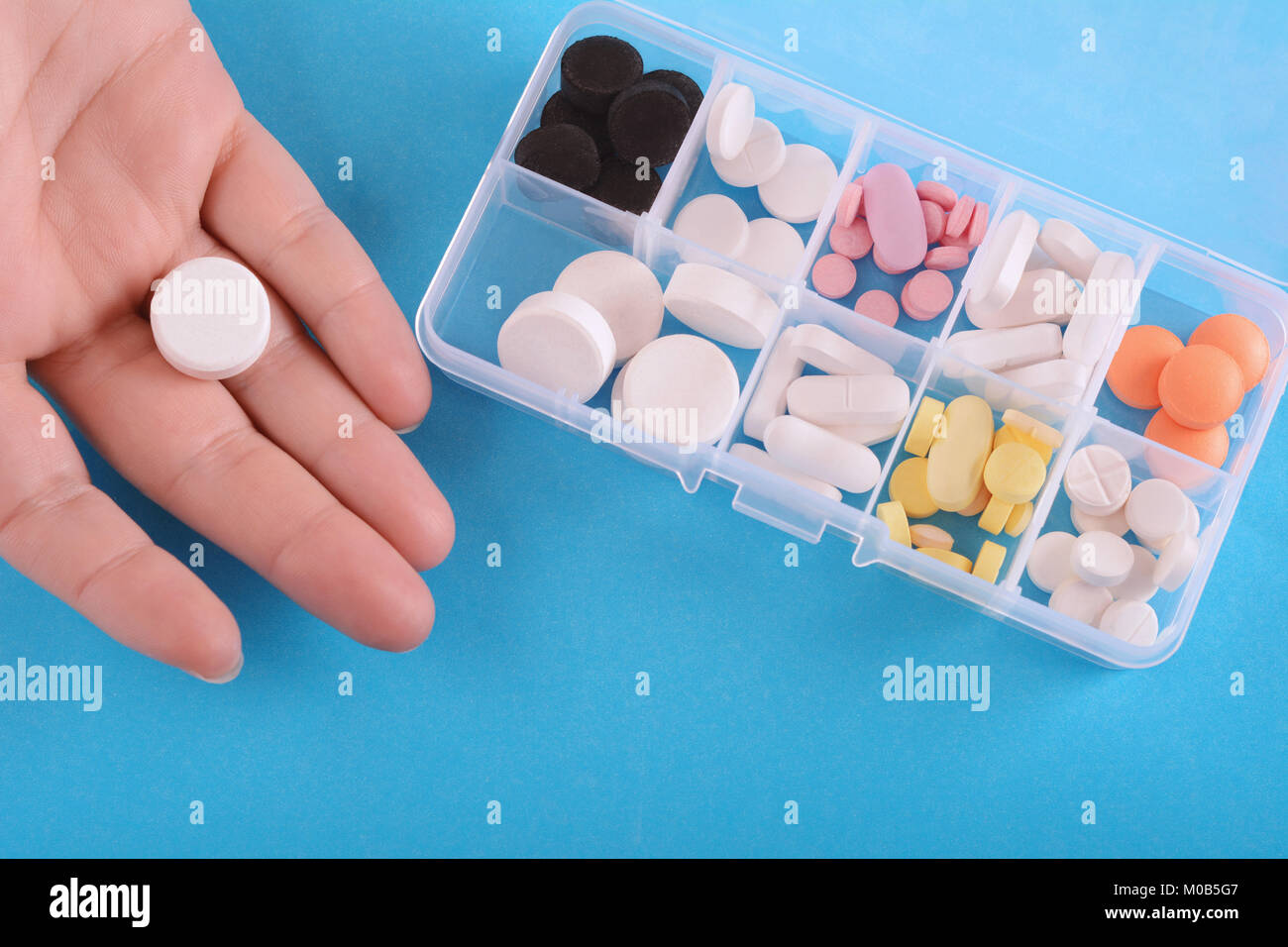 Close up of hand showing pill with medicine box. Blue background Stock ...