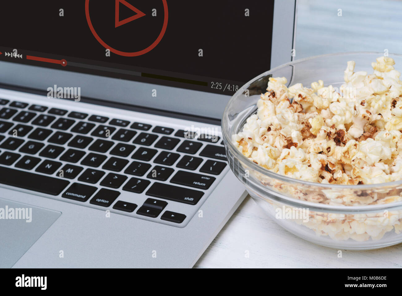 Popcorn in bowl and laptop playing movie. Entertainment concept Stock ...