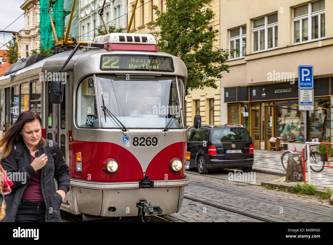 A woman walks past a Prague Tram a Tatra T3 waiting at a tram stop ...