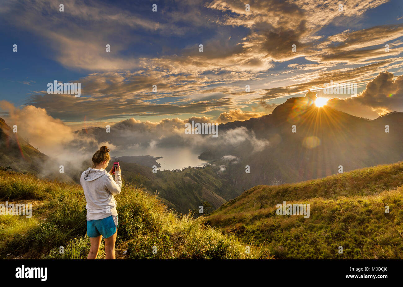 Tourist enjoying sunset view from crater of Mount Rinjani, Indonesia ...