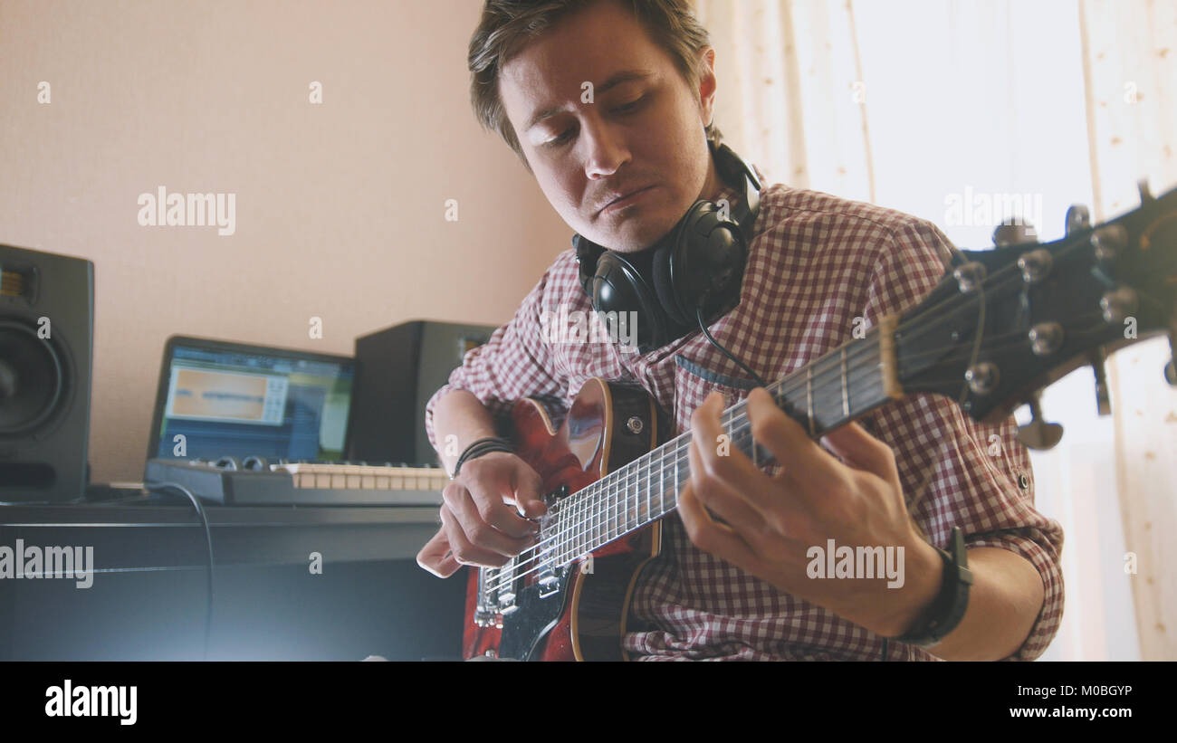Young attractive male musician composes and records soundtrack playing ...