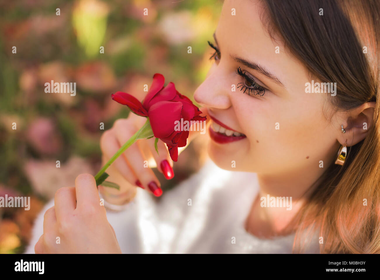 Happy Girl sniffing a red rose Stock Photo - Alamy