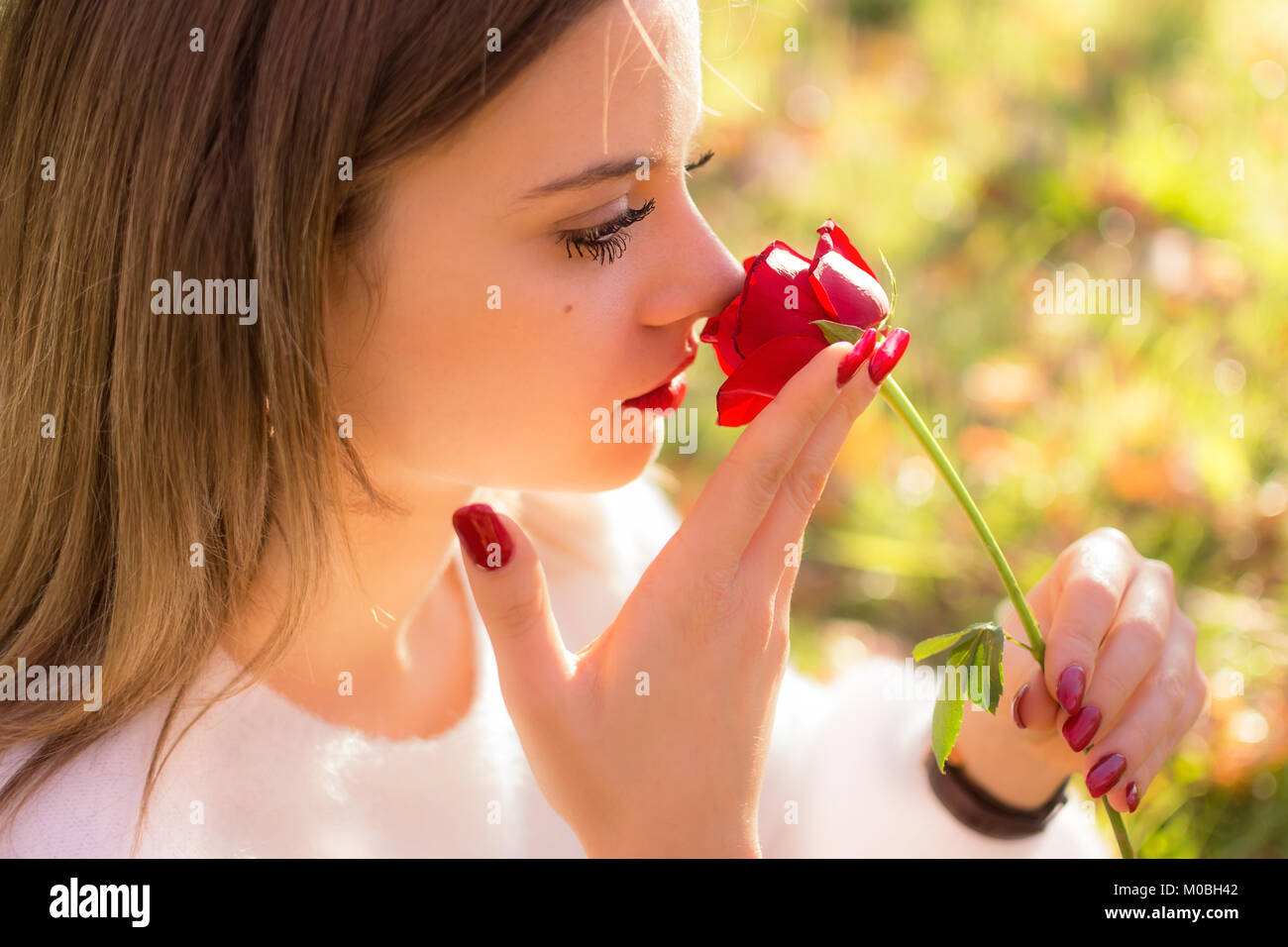 A Girl sniffing a red rose in San Valentine day Stock Photo - Alamy