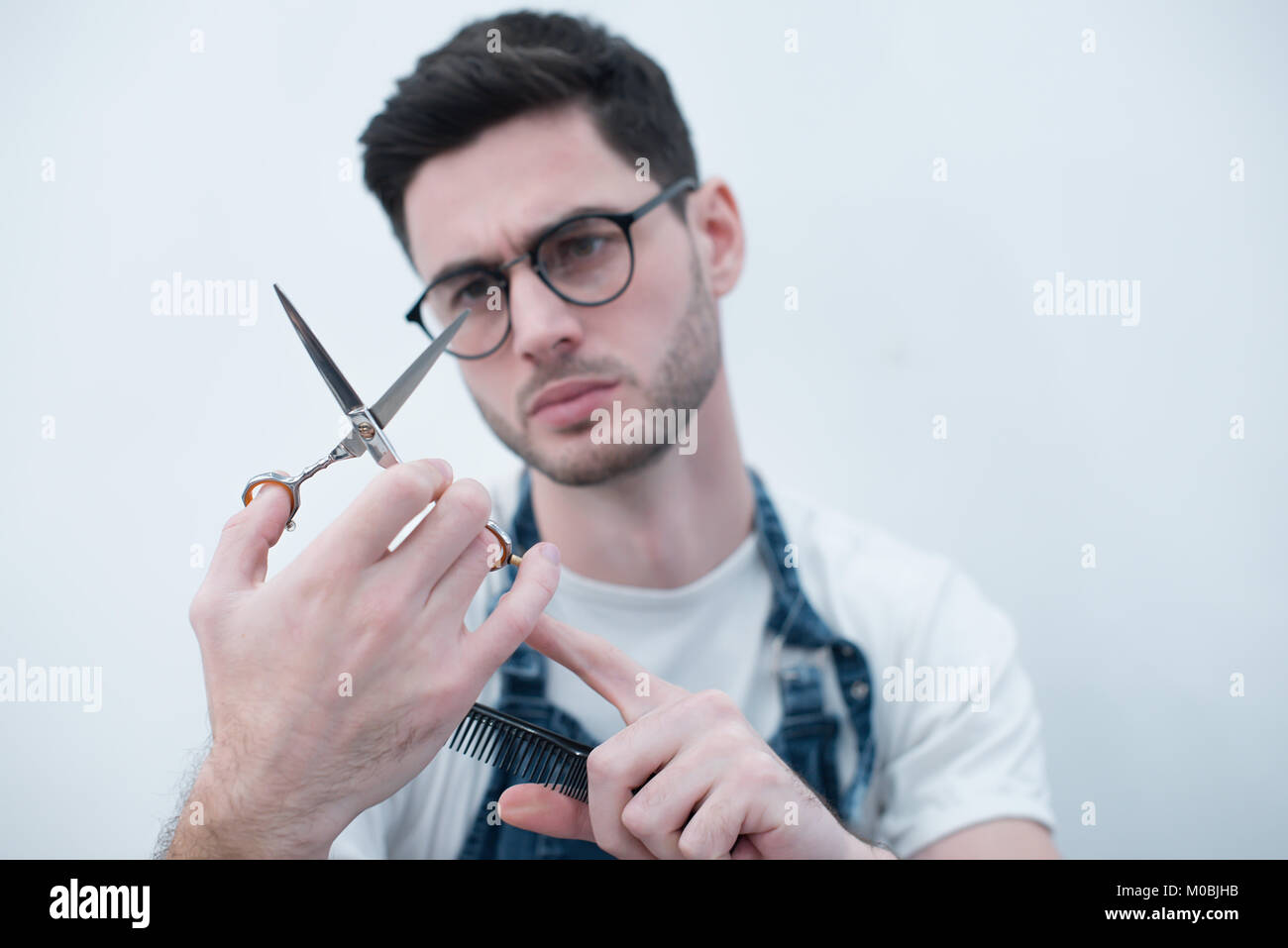 Barber keeps the scissors on his elongated hands against the background ...