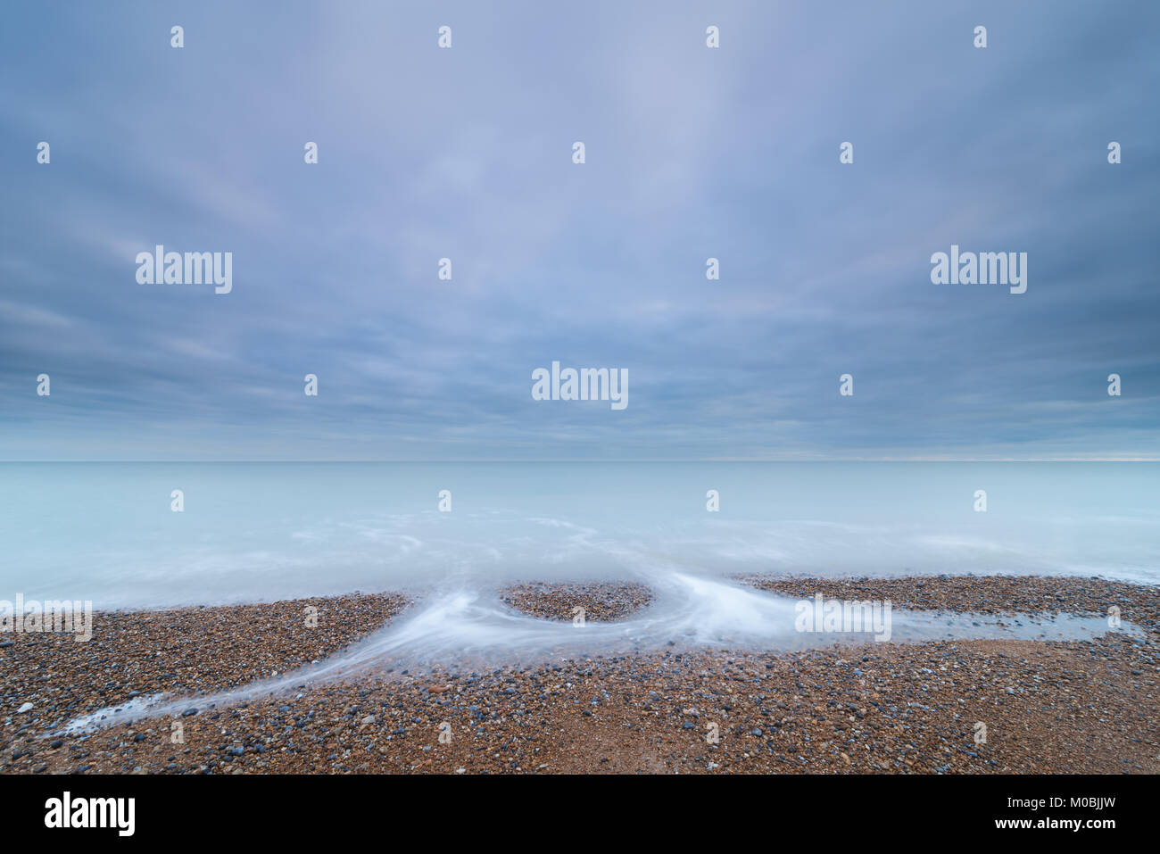 Receding tide on a shingle beach, making the shape of a fish tail. Like ...