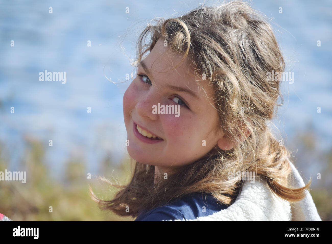 Pretty young girl smiling while looking over her shoulder Stock Photo ...