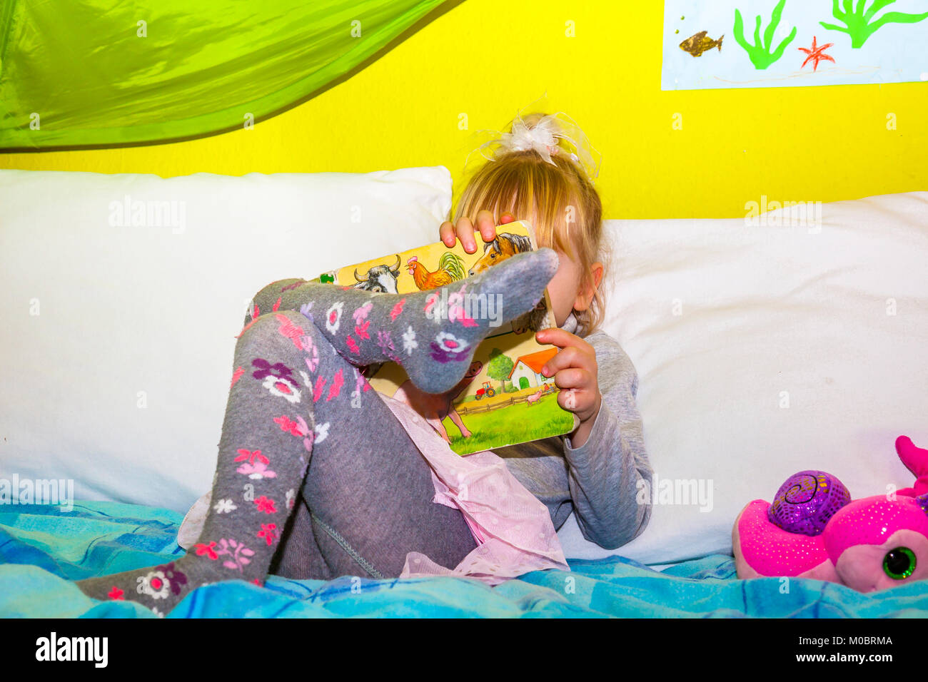 Little girl reading colourful book with pictures and text Stock Photo ...