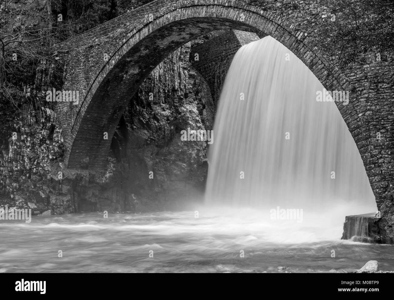 Beautiful cascading waterfalls under an old traditional stone bridge in ...