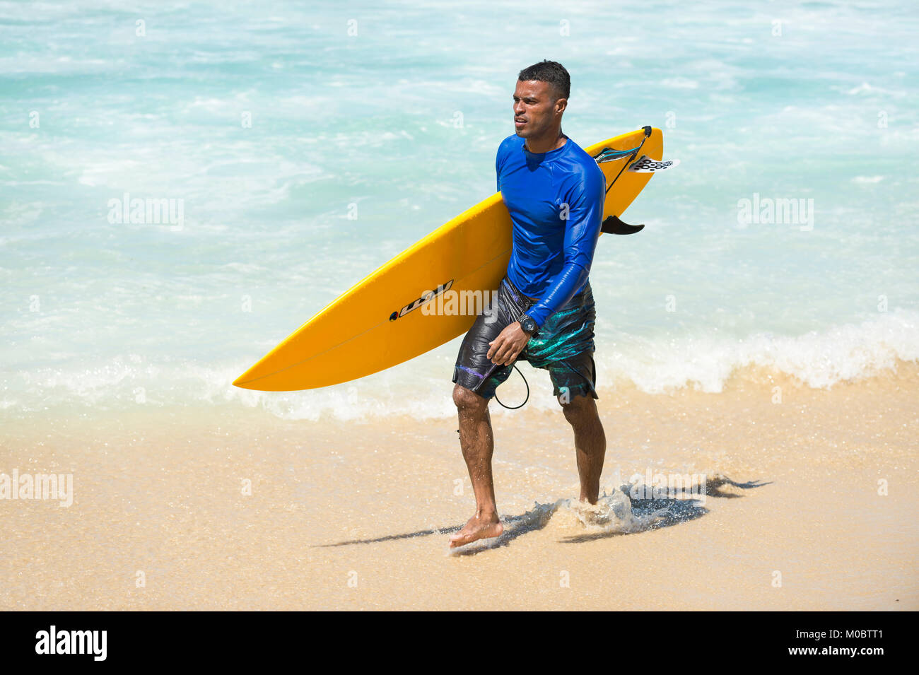RIO DE JANEIRO - FEBRUARY 9, 2017: Young Brazilian surfer walks with ...
