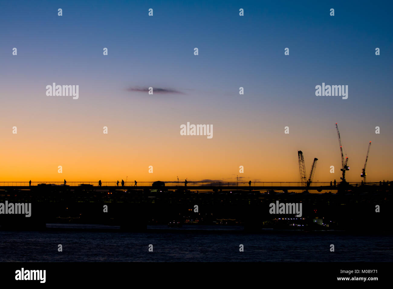 Silhoutted people crossing a city bridge at sunset Stock Photo - Alamy