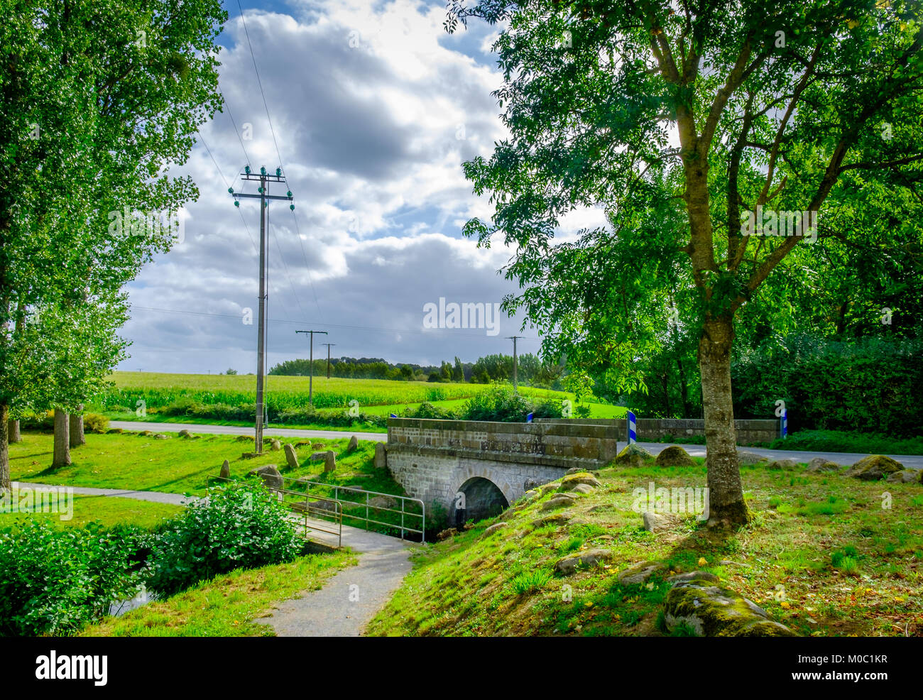 Country lane over a small bridge in the Orne countryside on an overcast ...
