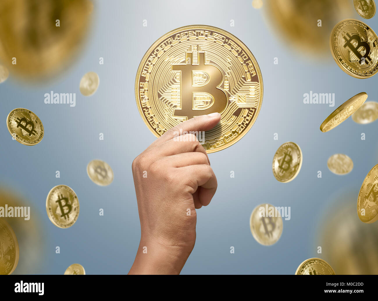 Man hands holding golden bitcoin with falling bitcoins on bright ...