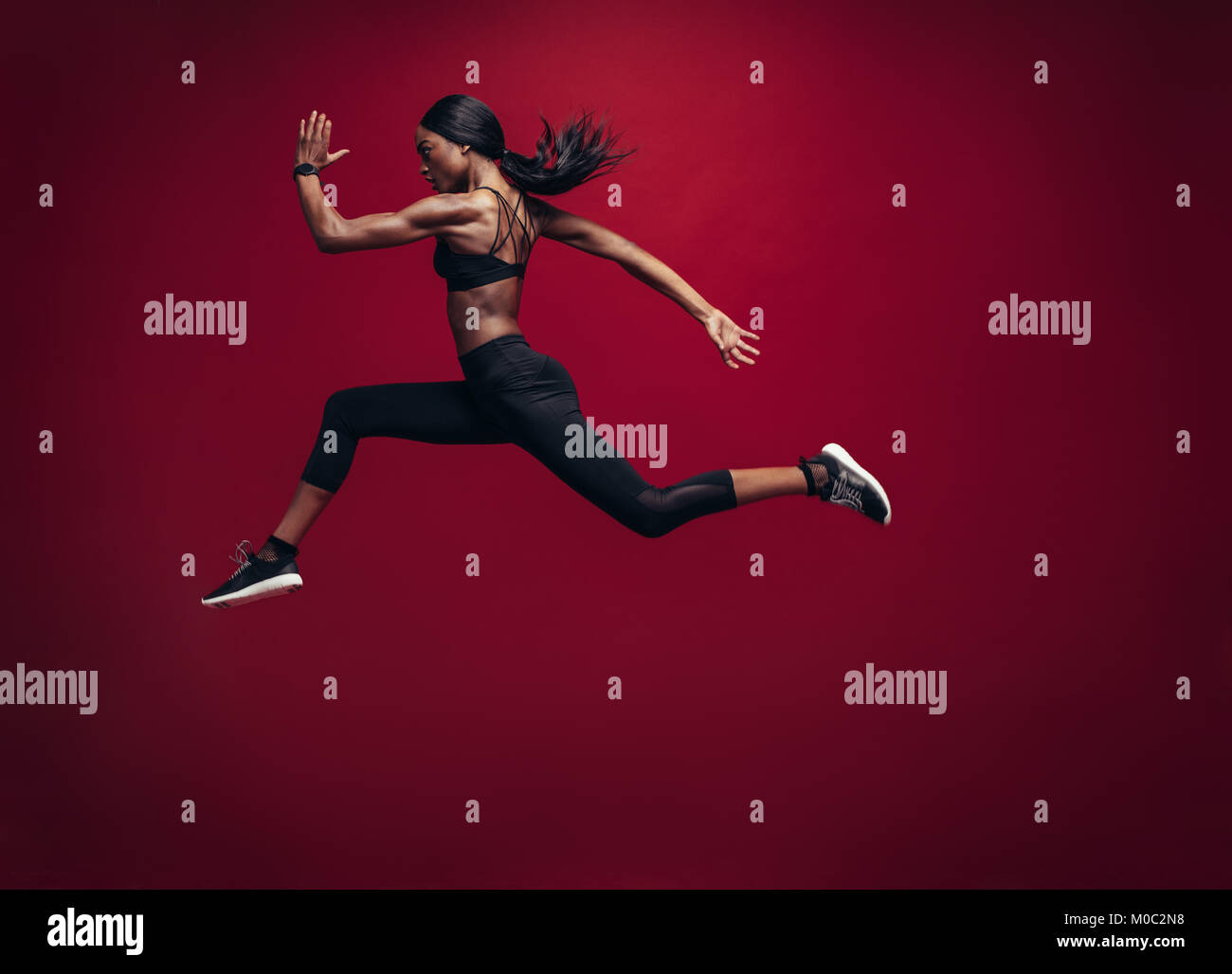 Female athlete running and jumping. Side view shot of healthy african ...