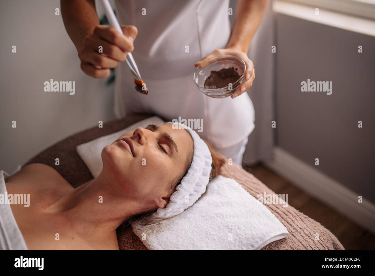 Cosmetologist applying cosmetic mask on the face of the woman in the ...