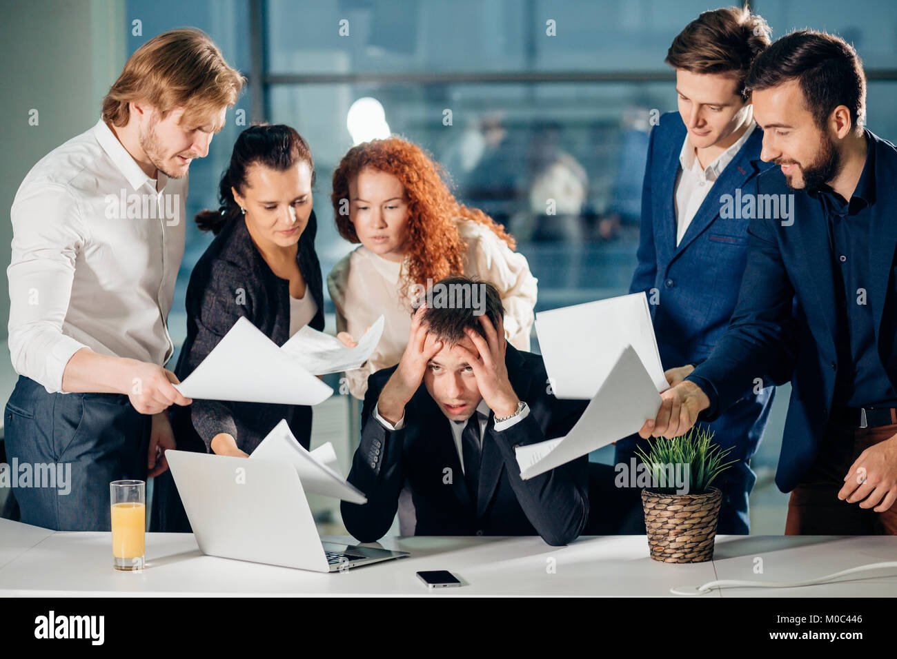 Stressed Business Man In Office surrounded by colleagues with documents ...