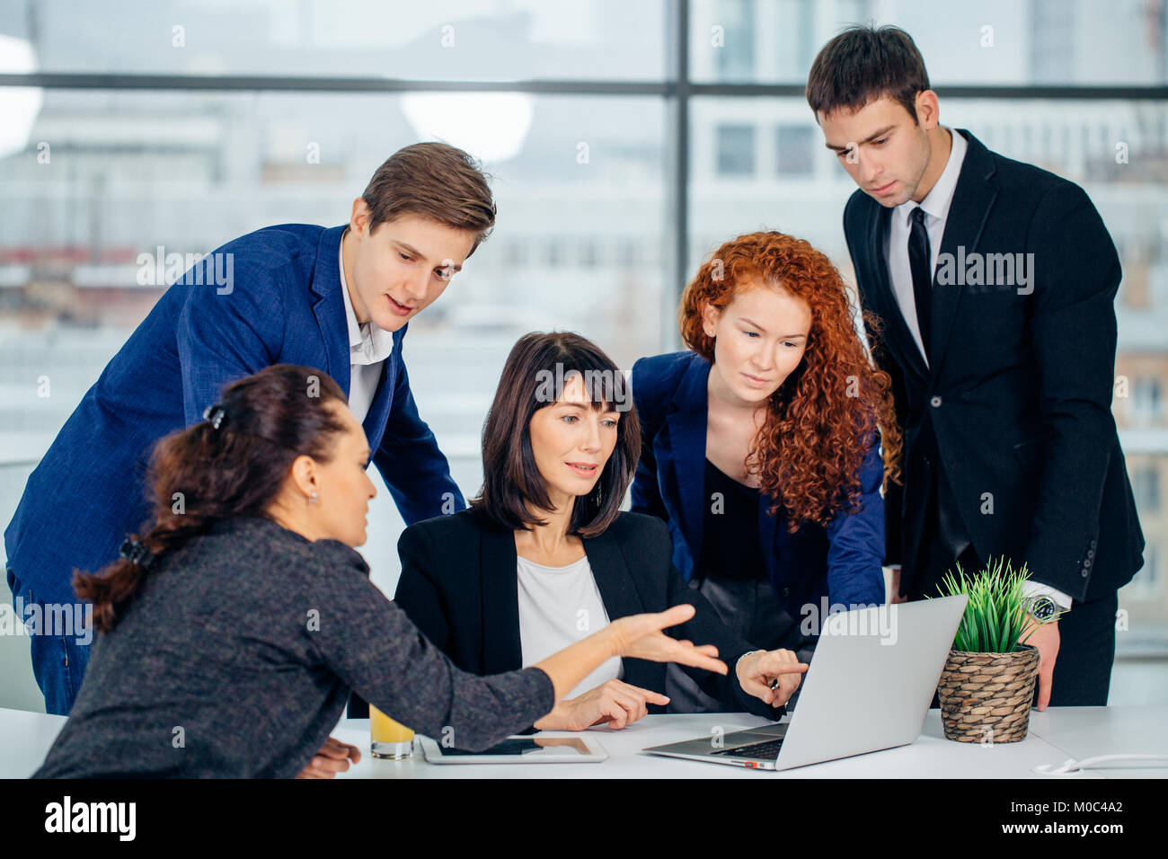 male and female business people around laptop computer in office Stock ...