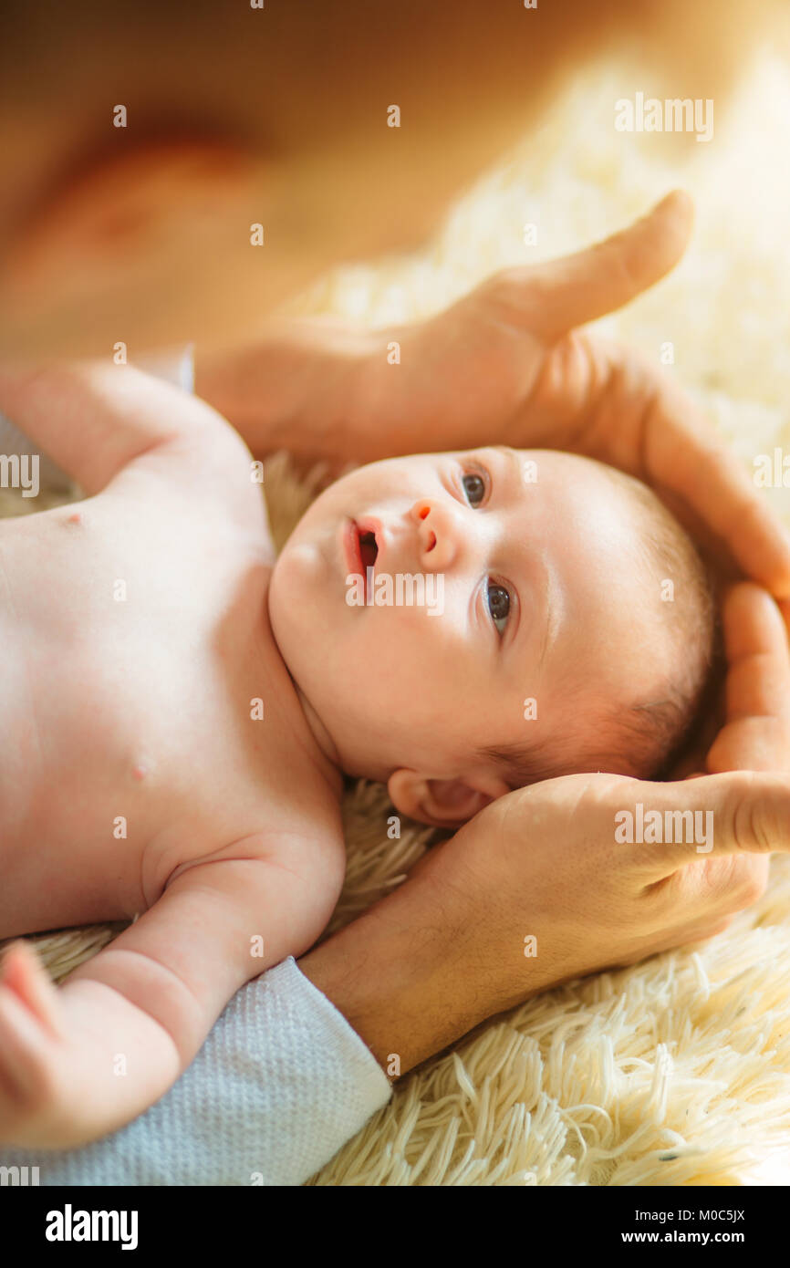 newborn baby lying down smiling looking at camera while father holding his head Stock Photo - Alamy