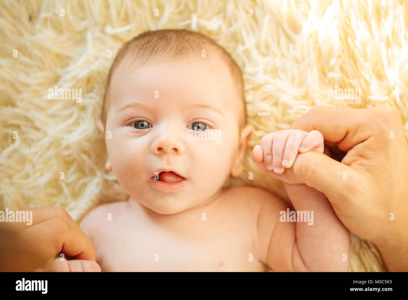 newborn baby lying down smiling looking at camera while father holding his head Stock Photo - Alamy