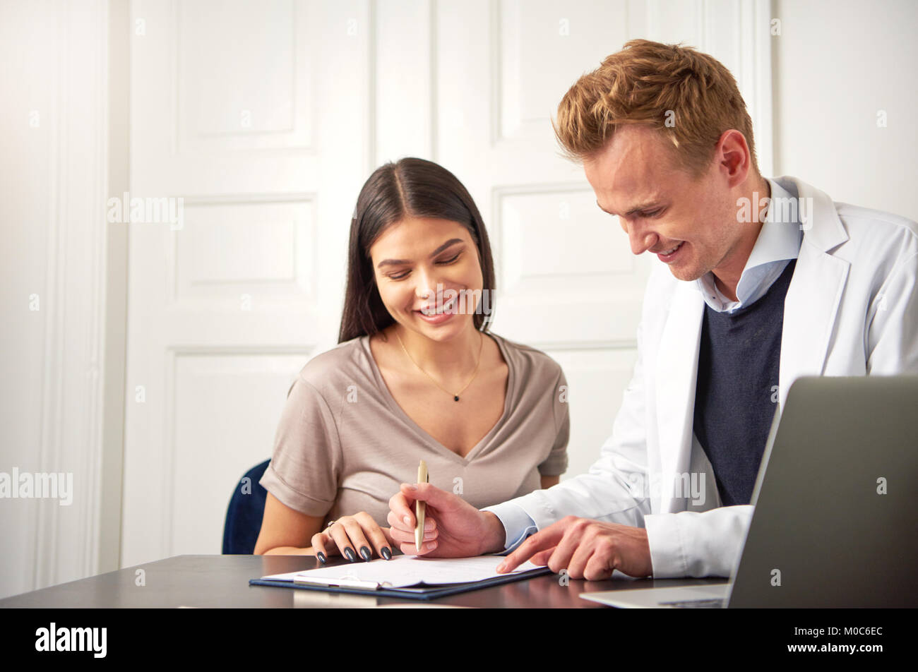 Cheerful female client signing papers with spa and beauty professional ... Cheerful female client signing papers with spa and beauty professional ...