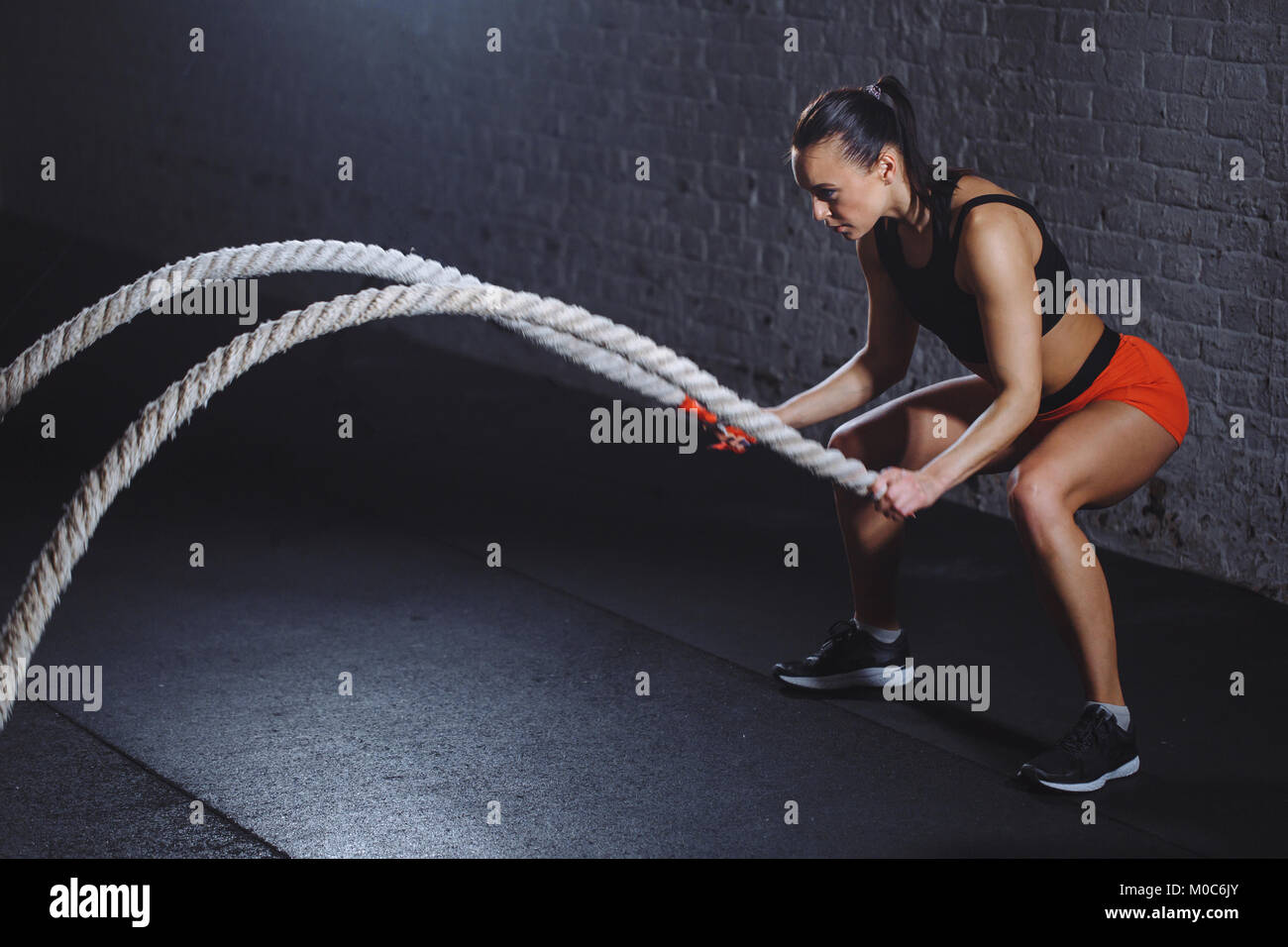 Athletic woman doing battle rope exercises at gym Stock Photo - Alamy