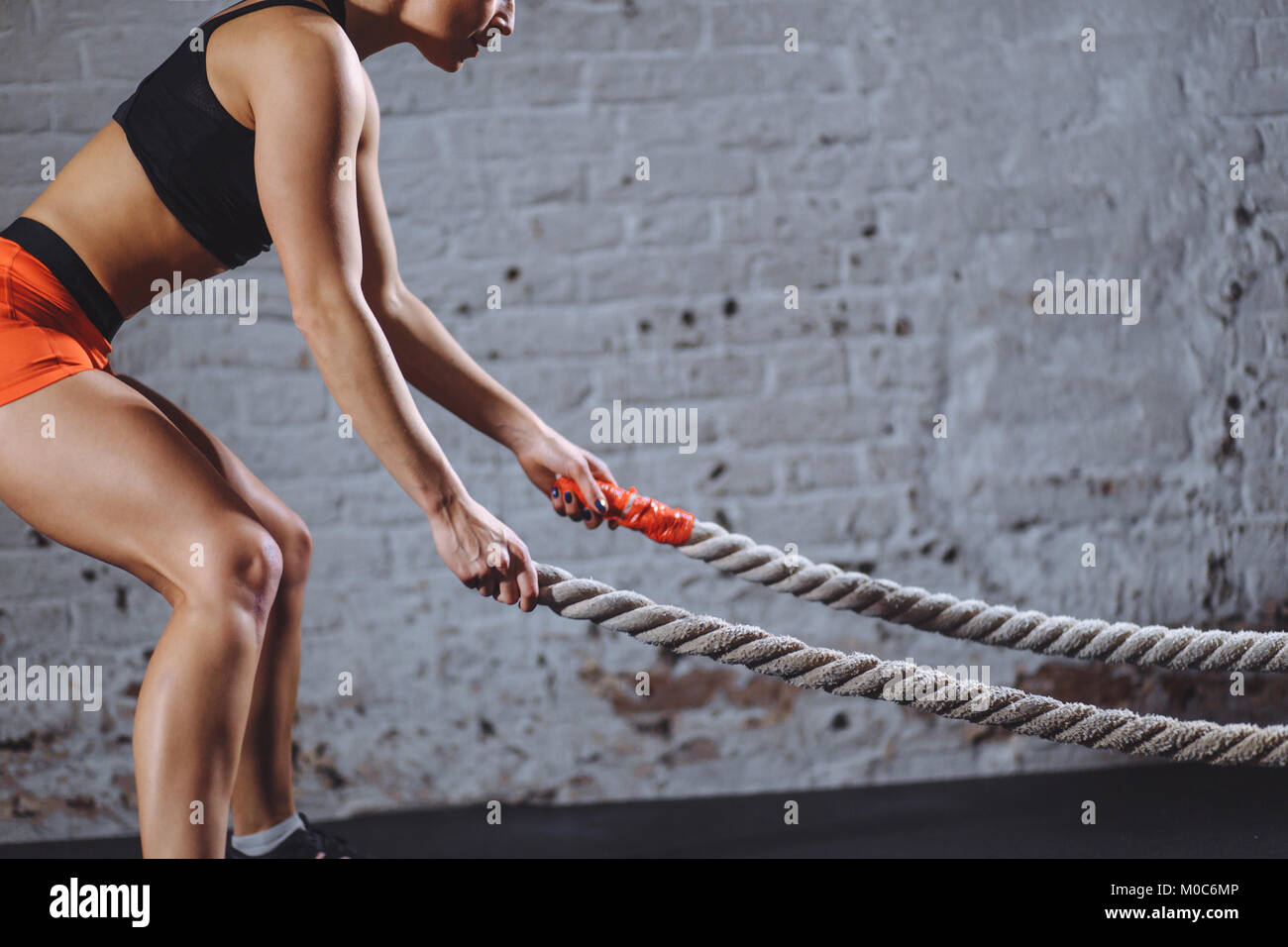 close up photo of Athletic woman doing battle rope exercises at gym ...