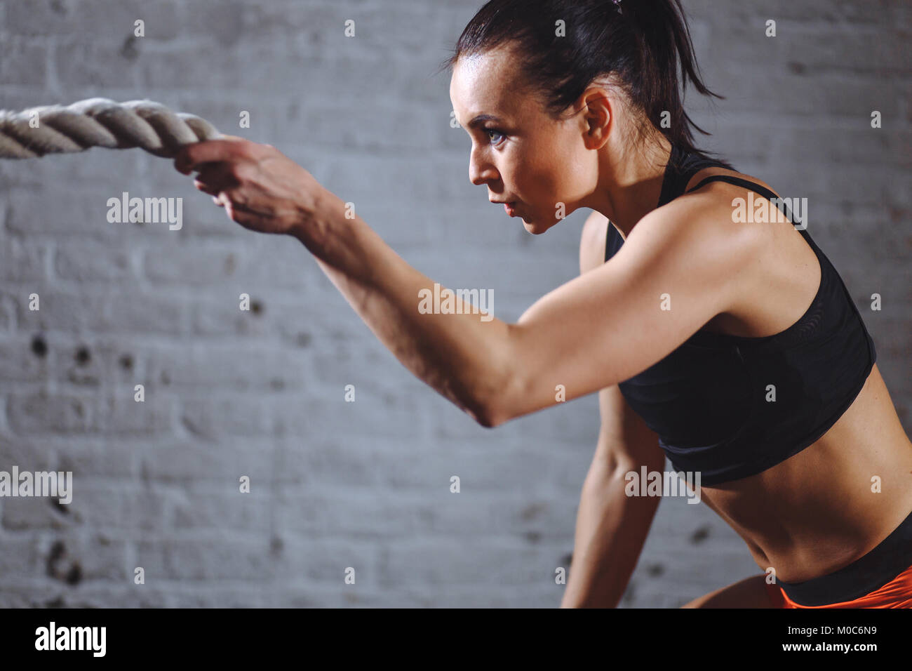close up photo of Athletic woman doing battle rope exercises at gym ...