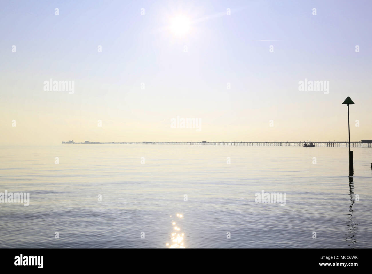 calm day with sun low in the sky, showing southend mile long pier and ...