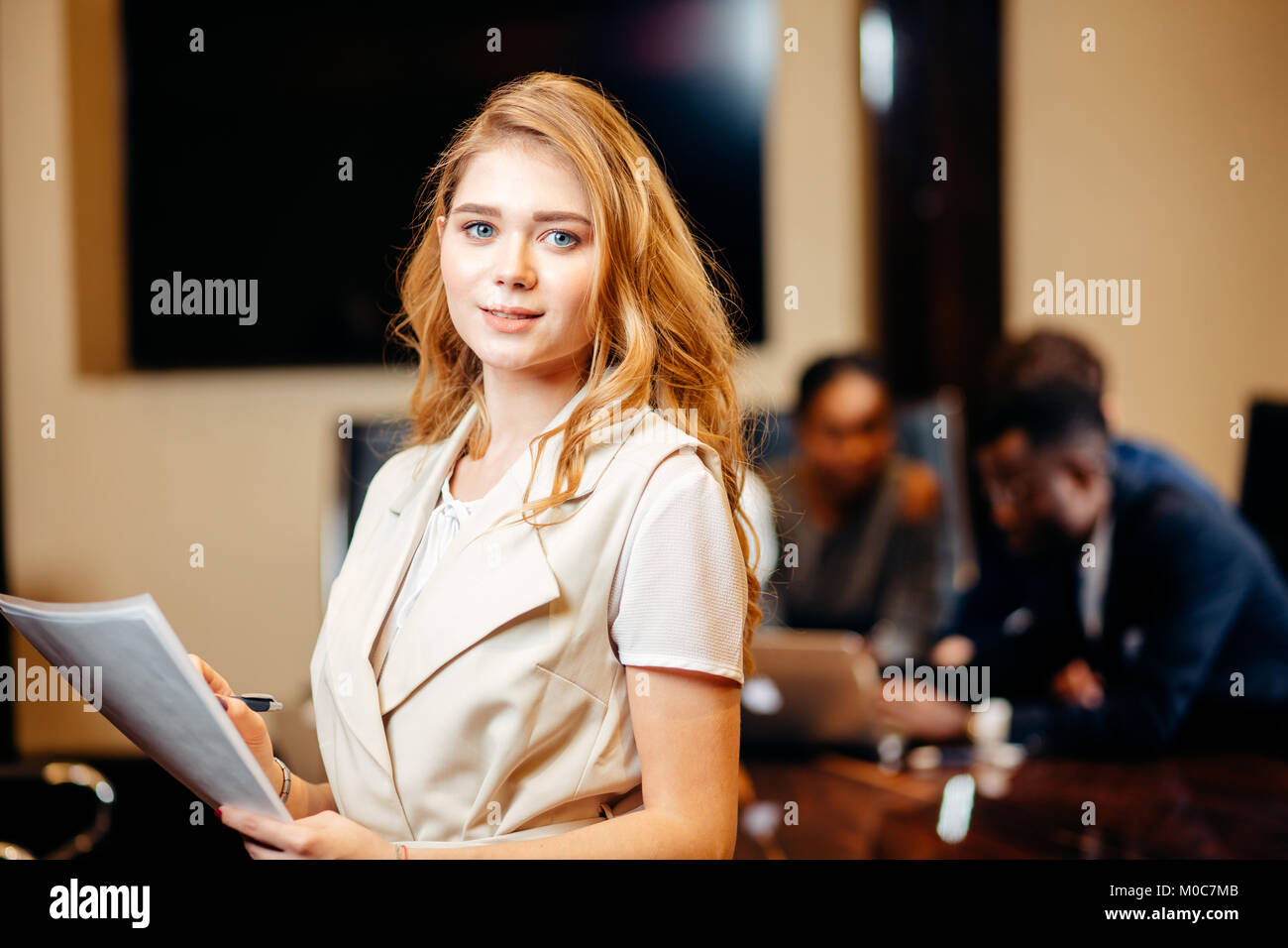 female employee looking at camera with workers on background Stock ...